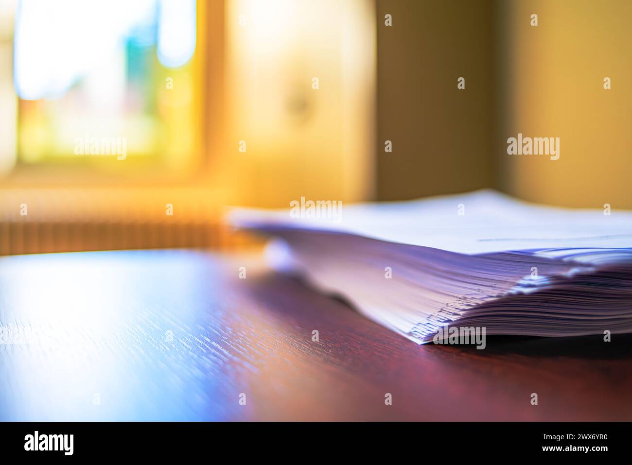 A pristine desk adorned with neatly stacked white A4 papers, creating ...
