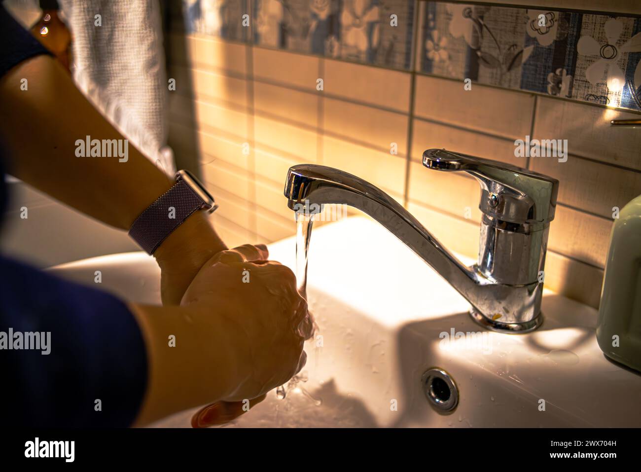 A woman diligently washes her hands, taking precautions against ...