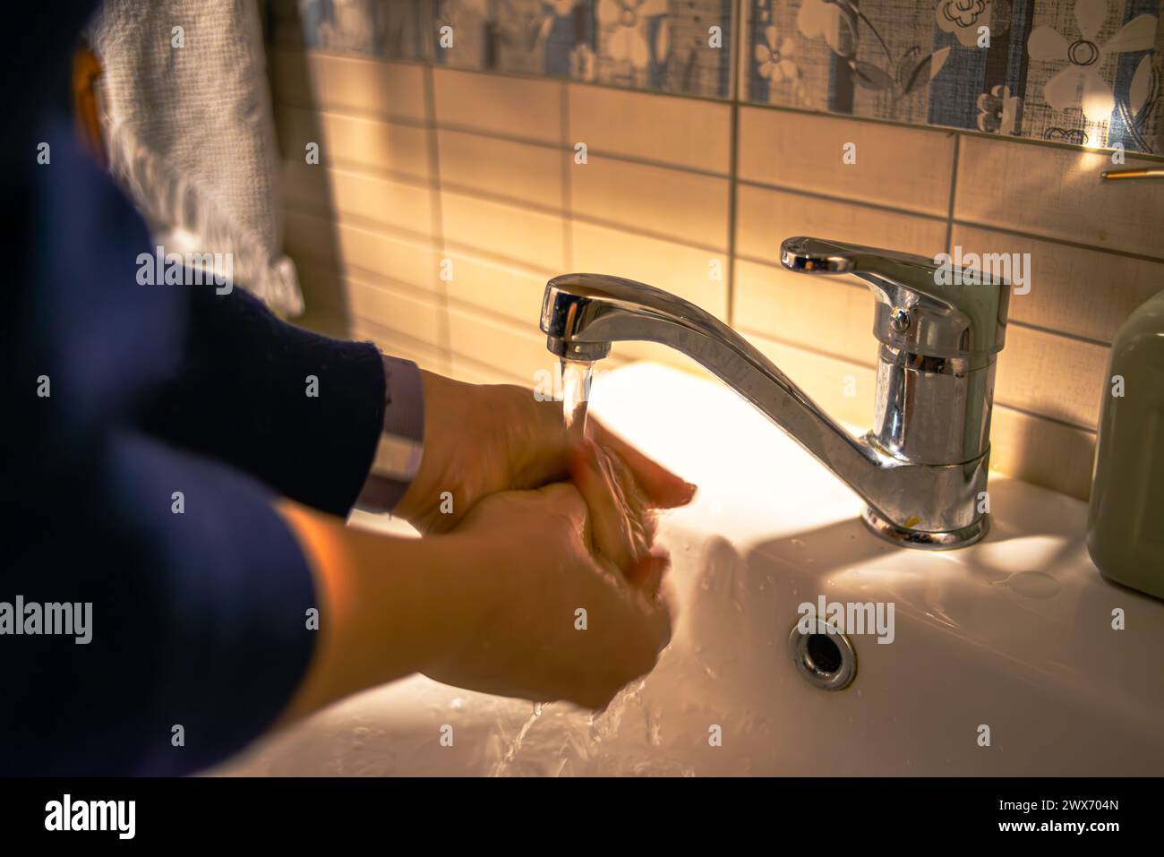 A woman diligently washes her hands, taking precautions against ...