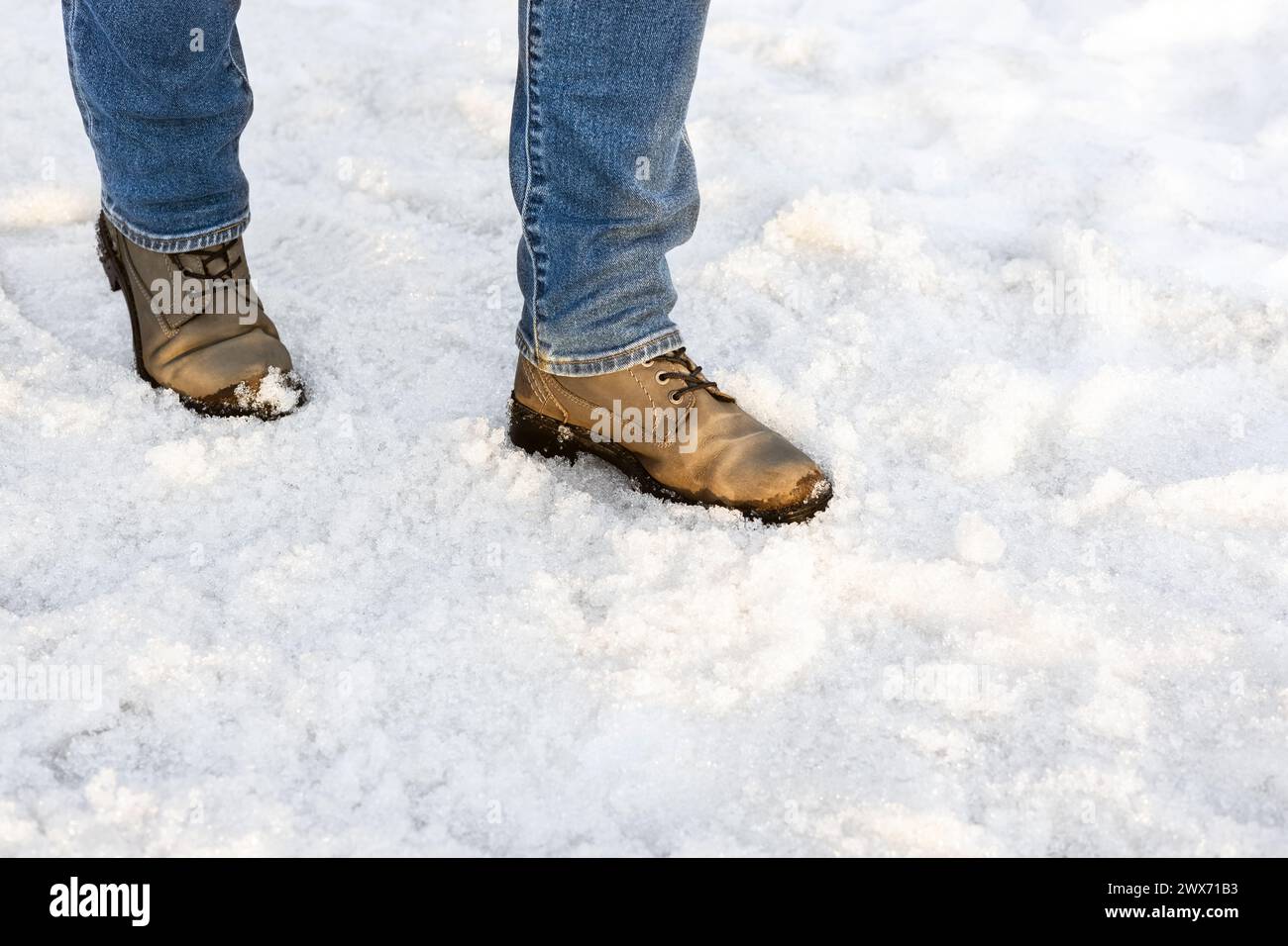 a man in boots walks through melted snow Stock Photo - Alamy