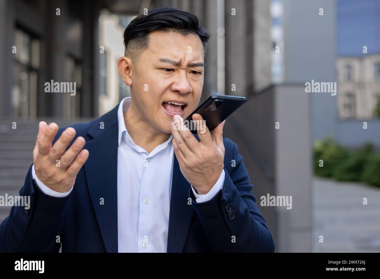 Close-up photo of angry young asian man businessman in suit standing ...