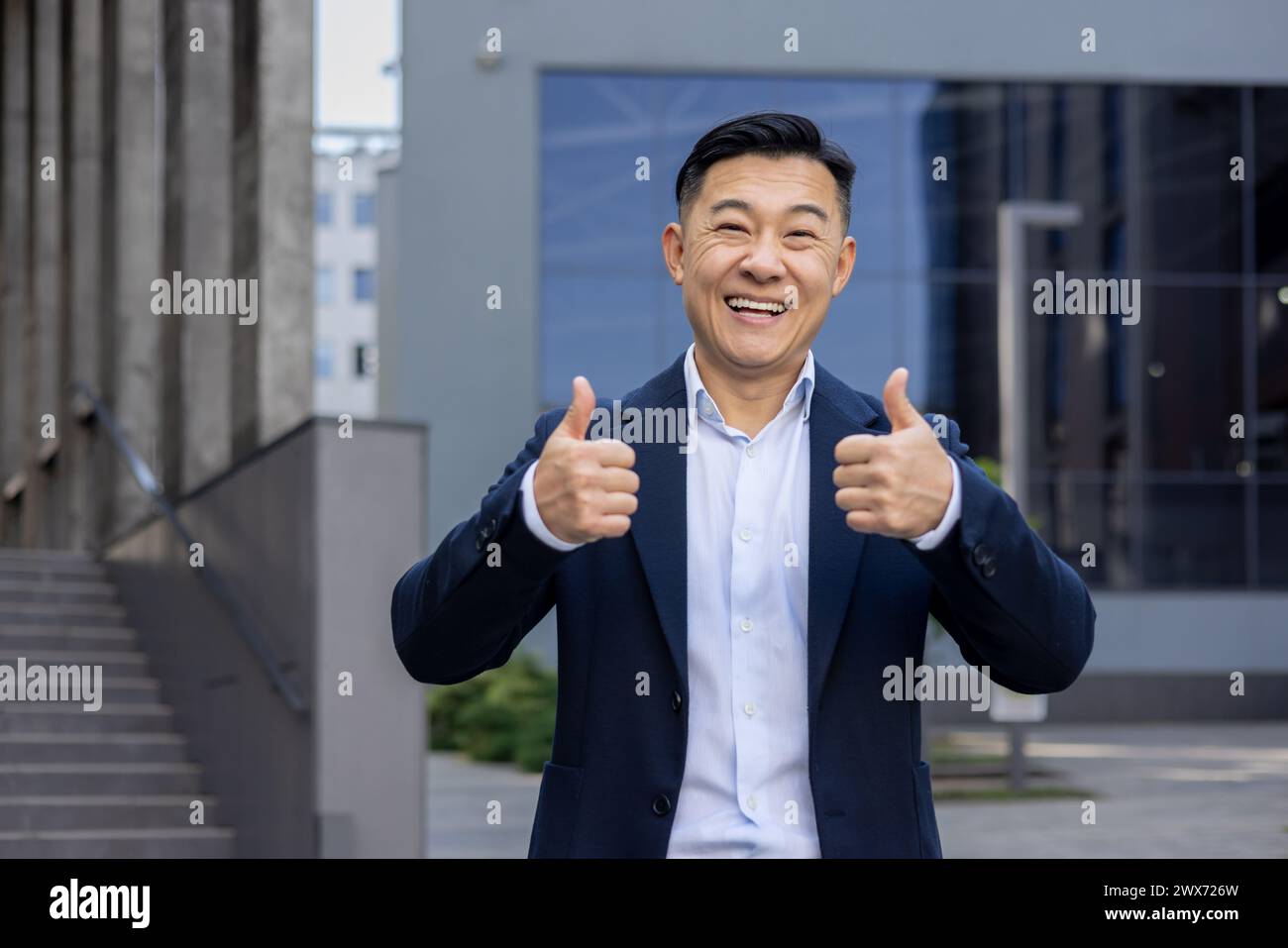 Portrait of a young successful Asian male businessman standing outside ...