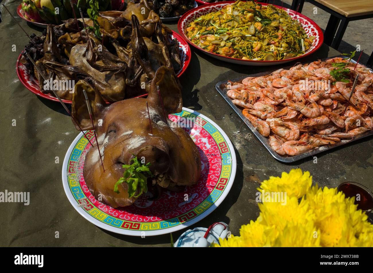 Big cooked pig head on plate on table among other dishes offerings to ...