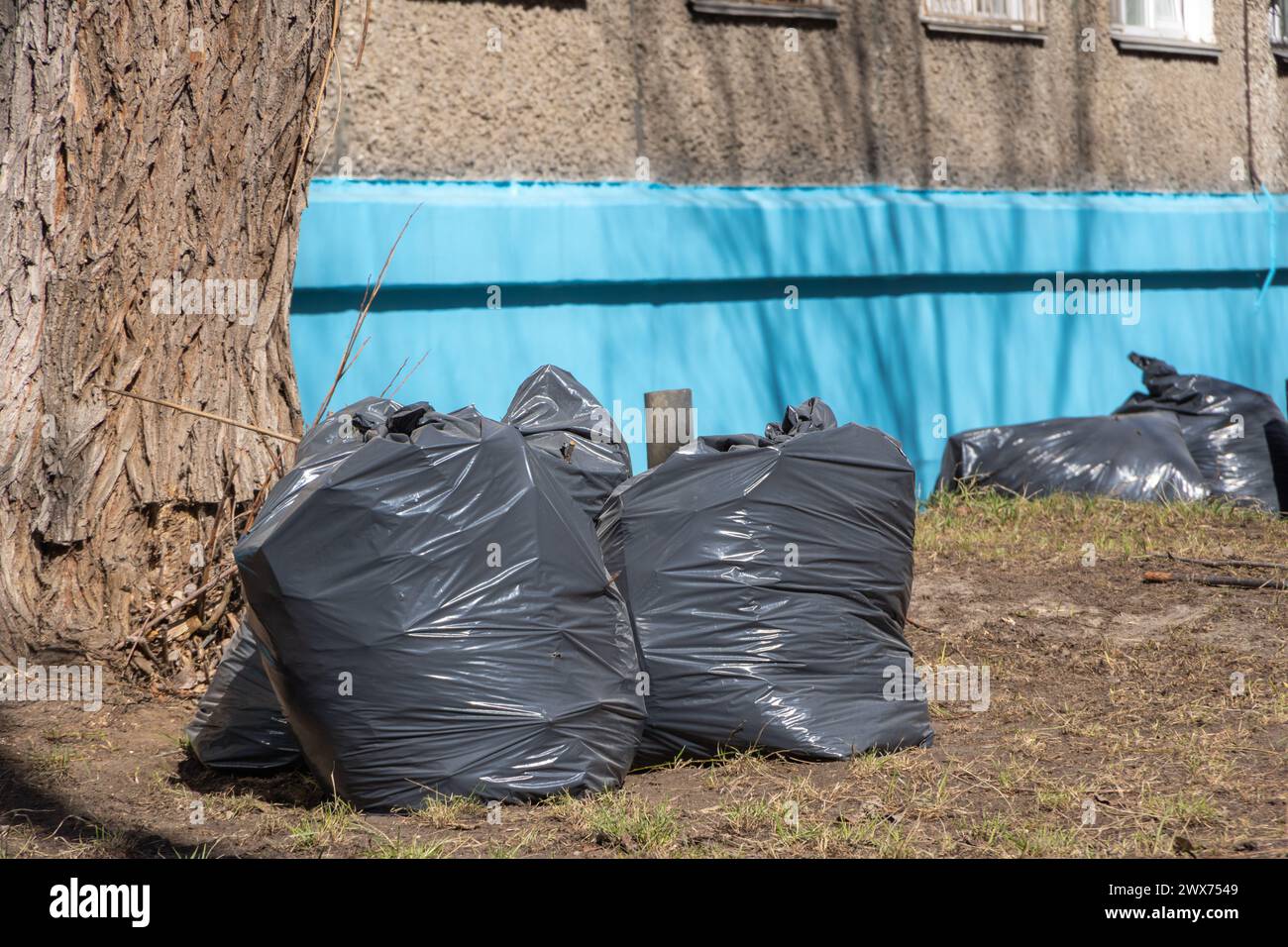 Pile of plastic garbage bags on the roadside near the city building ...