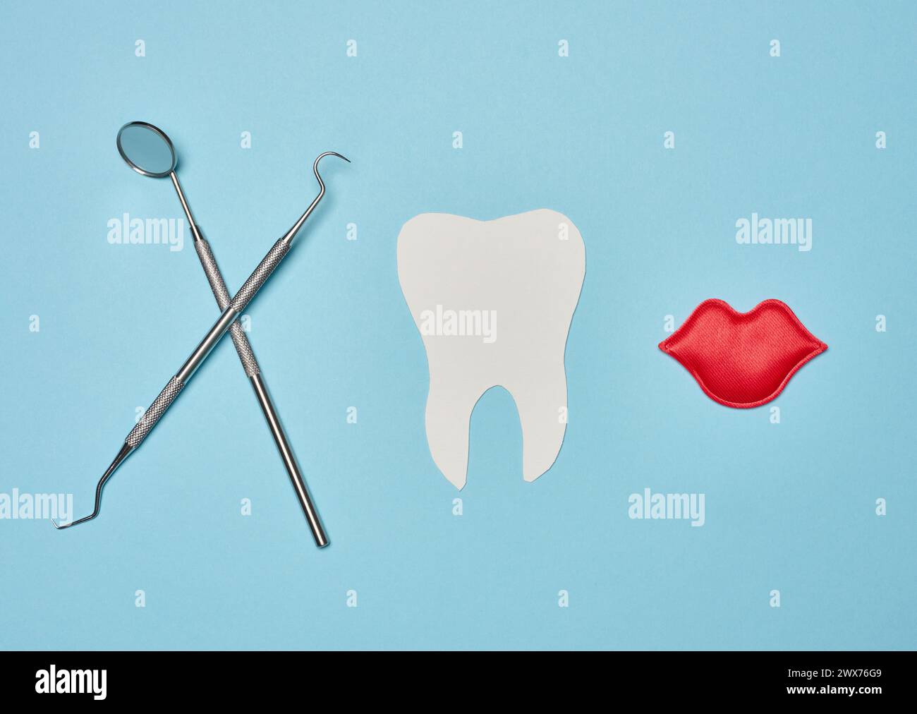 Paper human tooth and dentist medical instruments on blue background ...