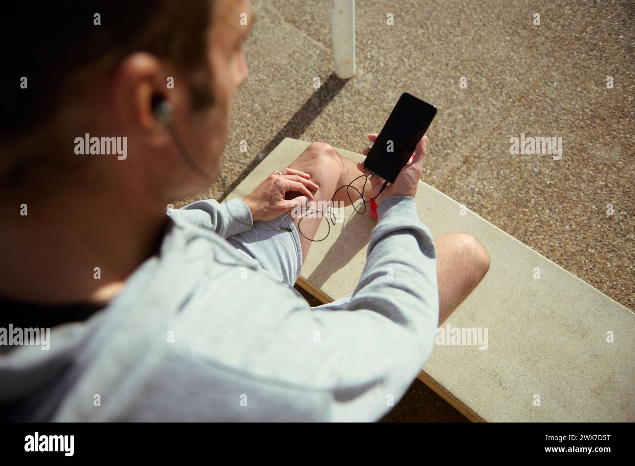 Overhead view of young man using mobile phone with blank black mockup ...