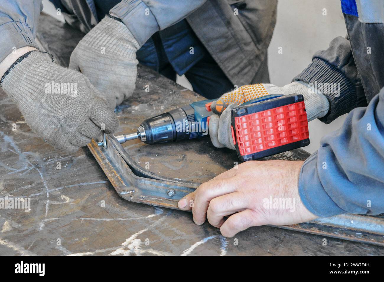A worker on a construction site operates a drill to cut through a metal ...