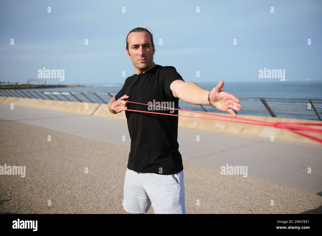 Young athlete doing arms, biceps and shoulder exercises with resistance ...