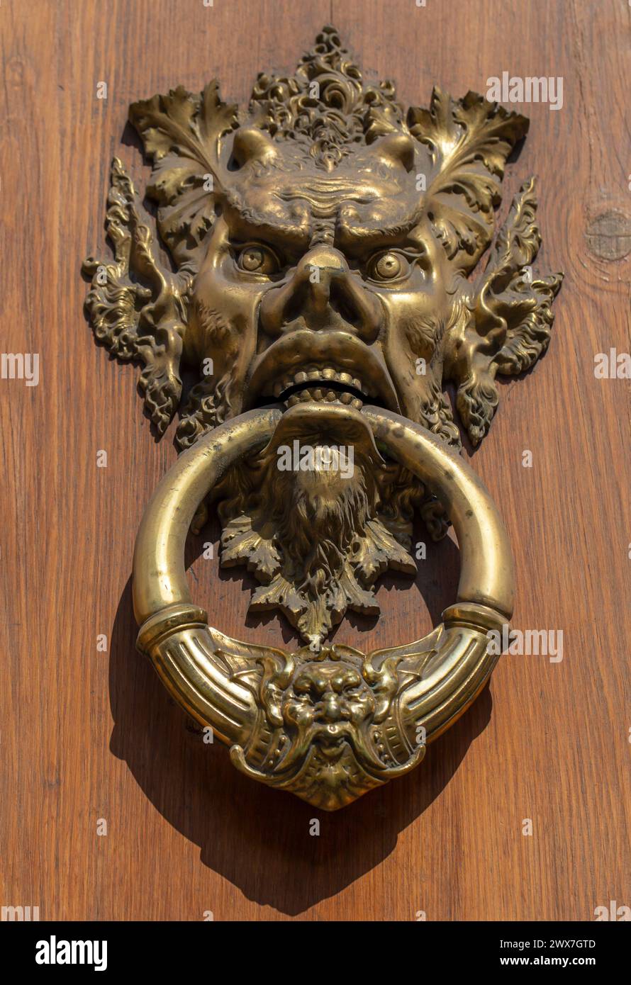 Devil head door knocker on an old door Stock Photo - Alamy
