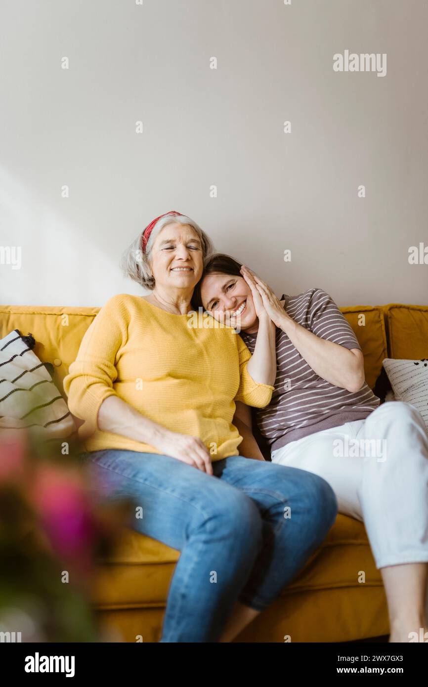 Portrait of smiling woman sitting with elderly mother-in-law on sofa at home Stock Photo - Alamy