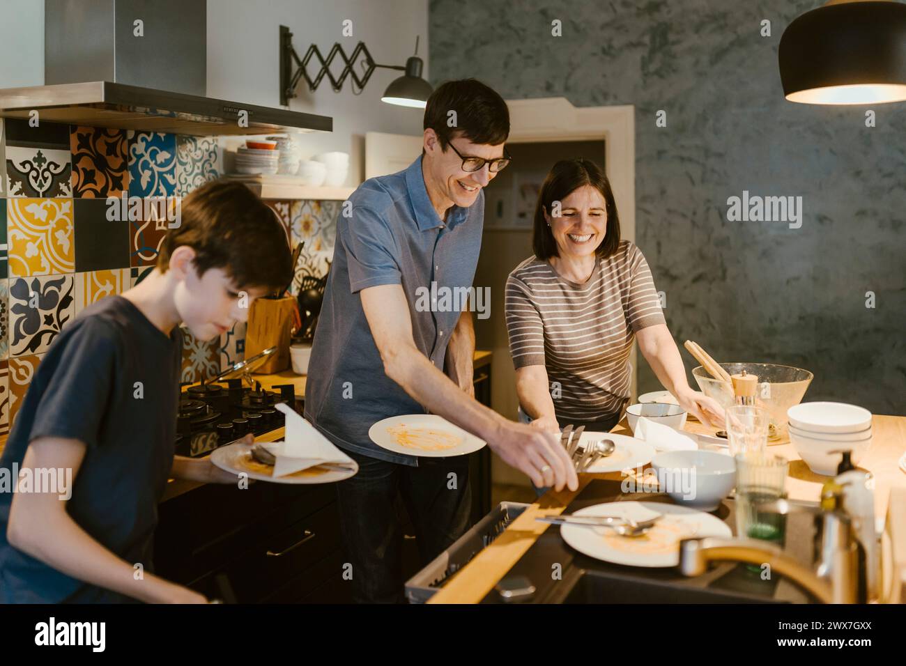 Family helping each other in clearing plates after dinner at home Stock ...
