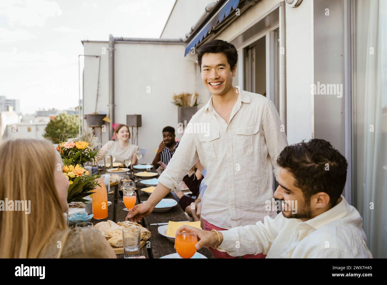 Portrait of smiling man with male and female friends enjoying at dinner ...
