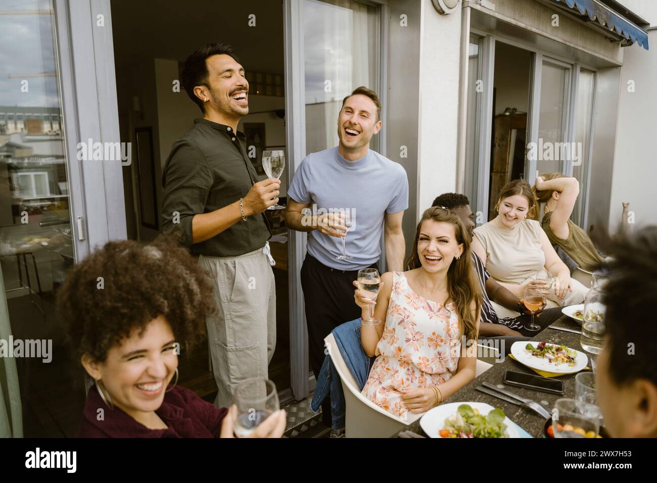 Group of cheerful friends laughing while celebrating dinner party in ...
