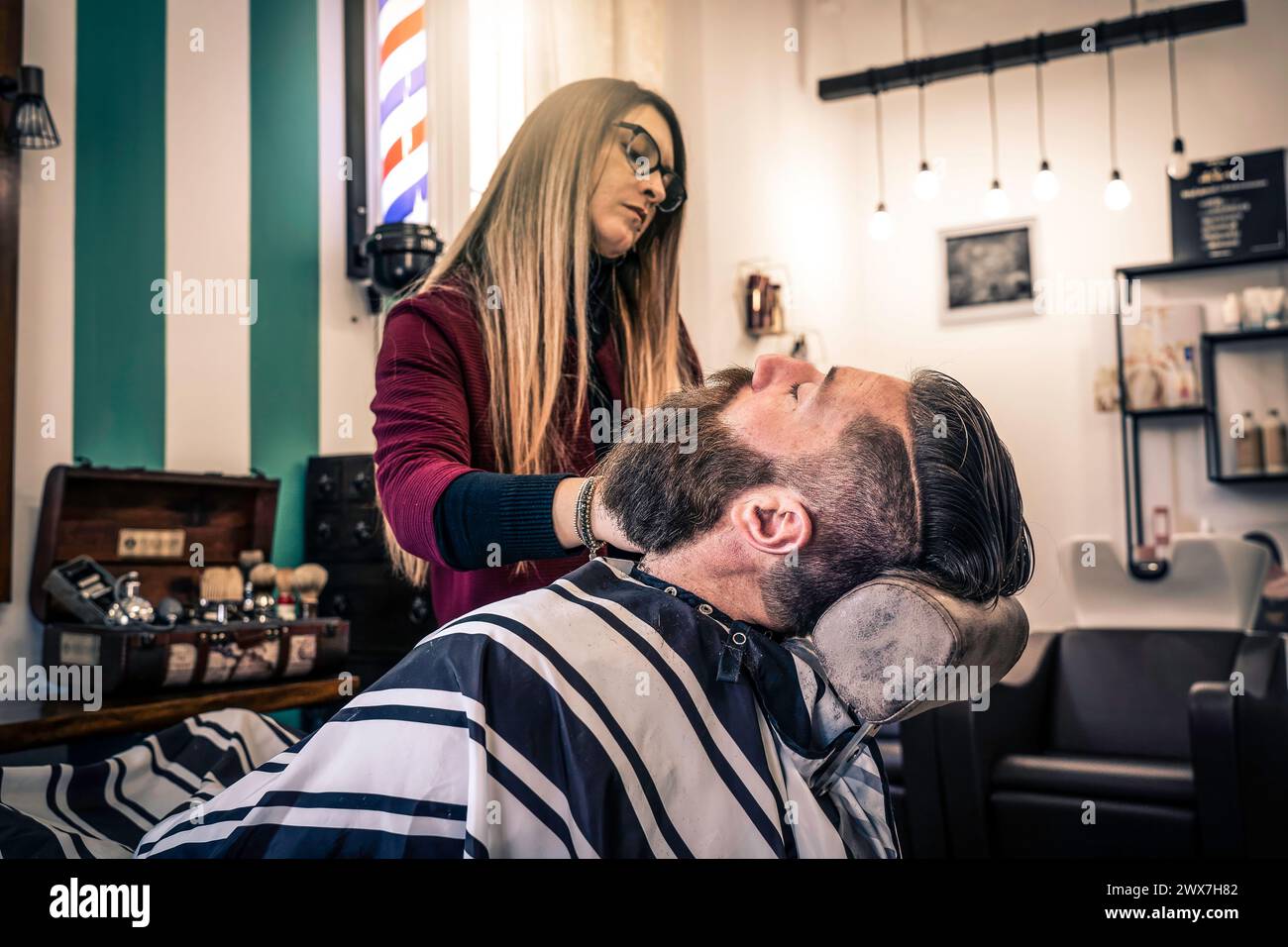 Woman skilled stylist at work in a trendy barber shop. Careful ...