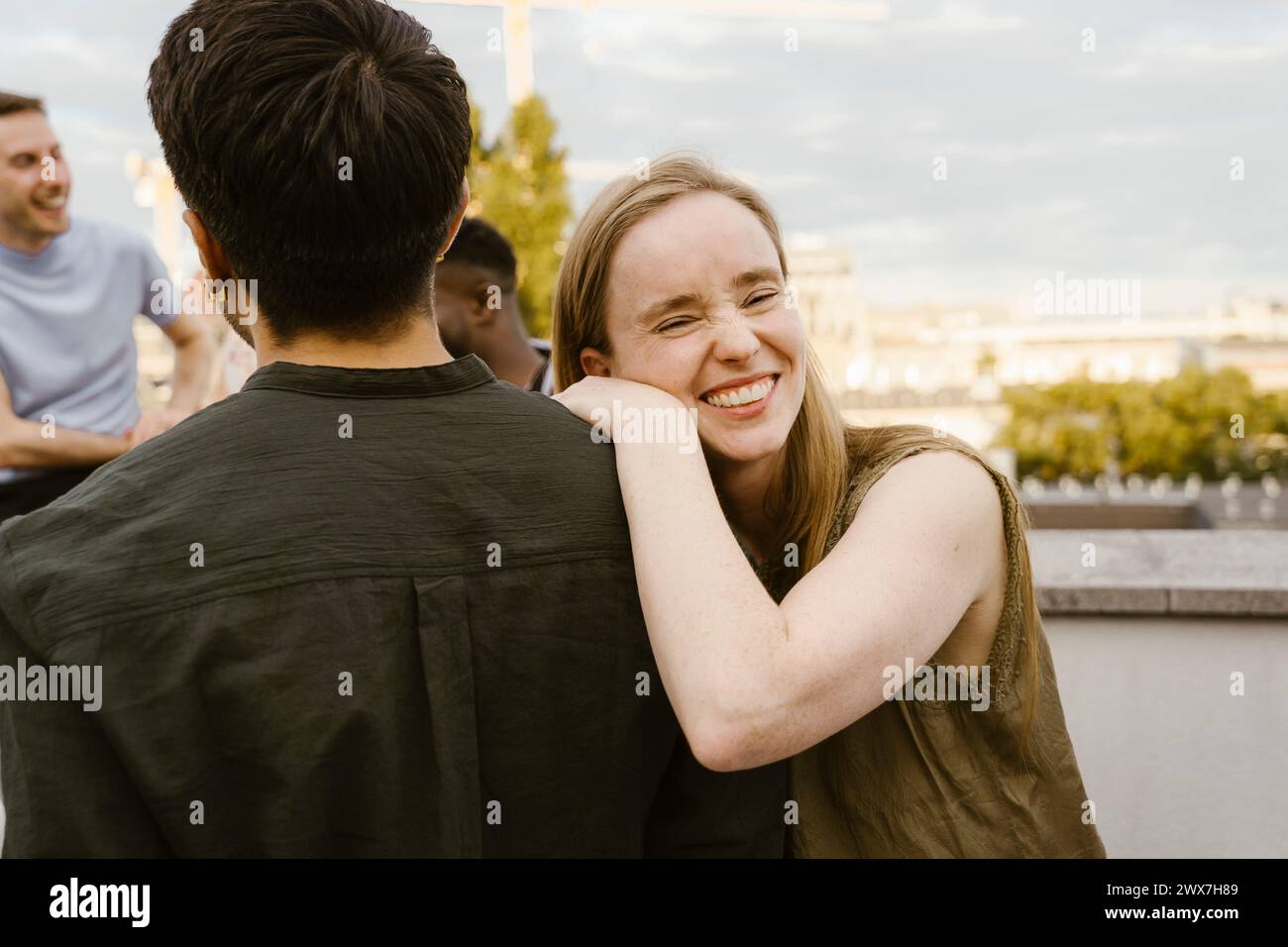 Portrait of smiling woman laughing while leaning on male friend's ...
