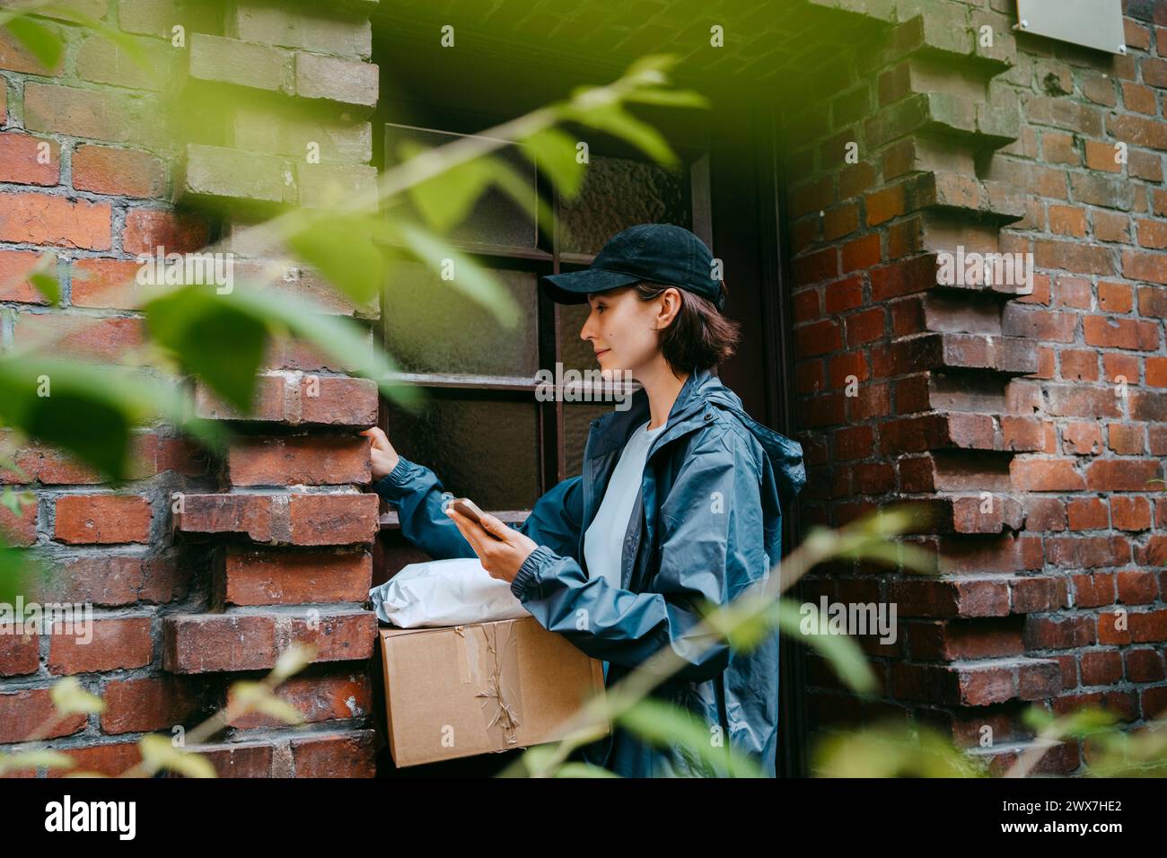 Female delivery person ringing doorbell while arriving with parcel ...