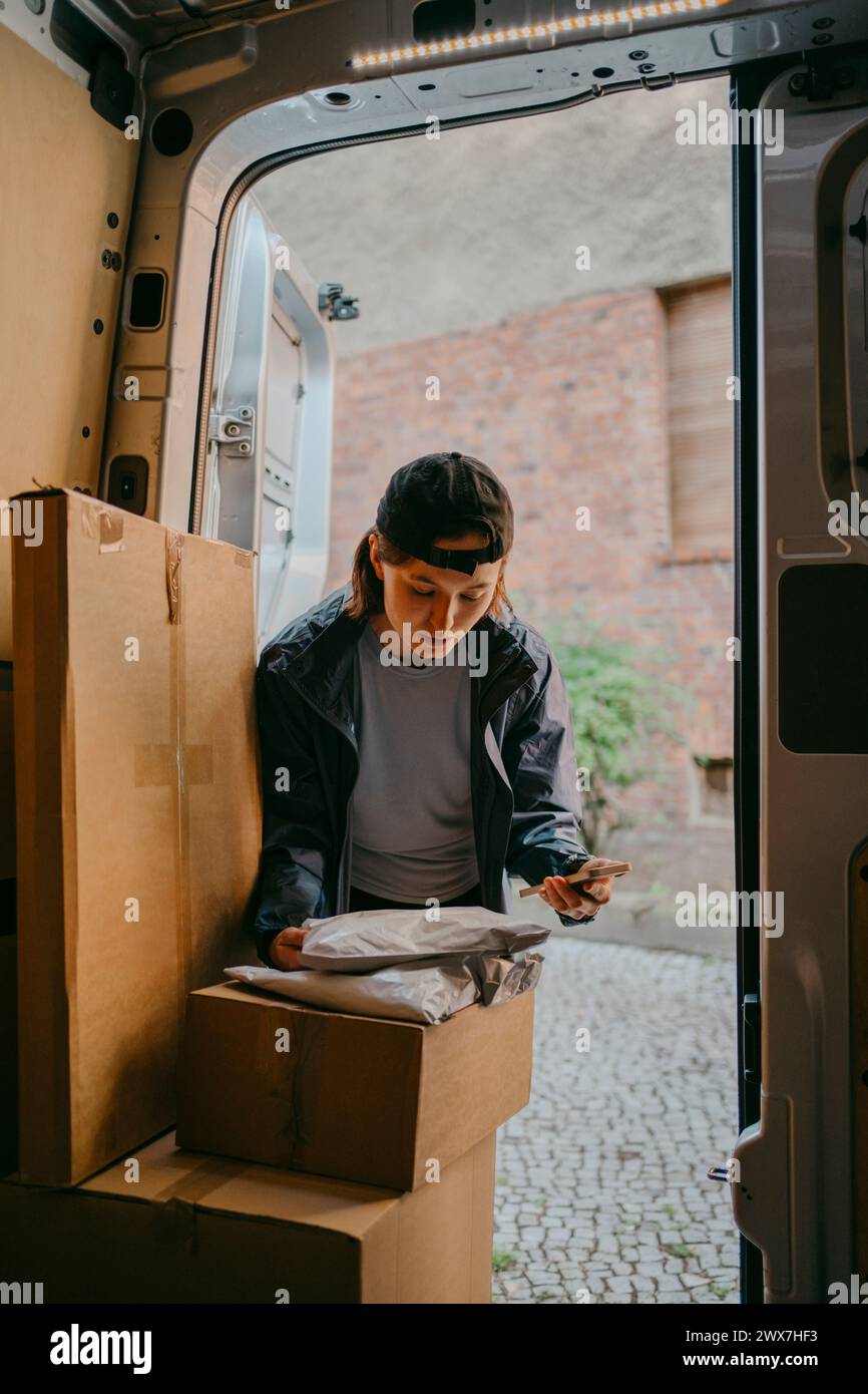Female courier delivery person taking inventory of parcels while ...