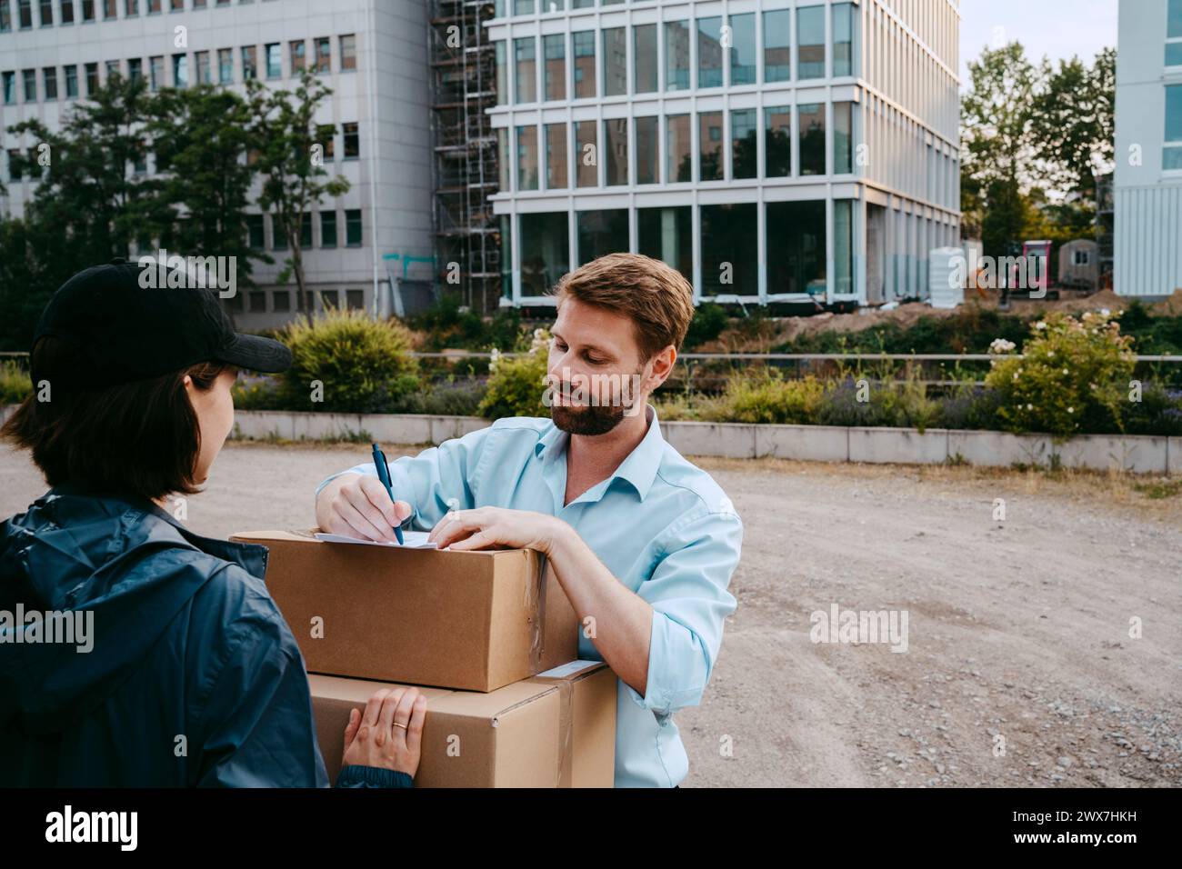 Mature man signing on documents while receiving packages from delivery ...