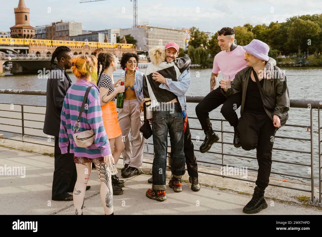 Happy non-binary friends greeting each other near on promenade in city ...