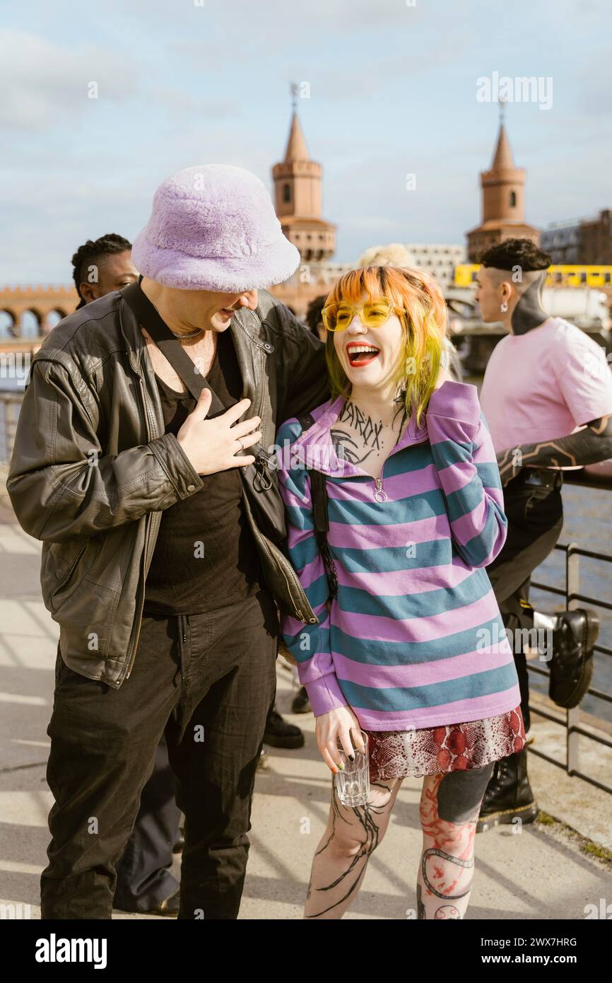 Gay man standing with arm around female friend on promenade in city ...