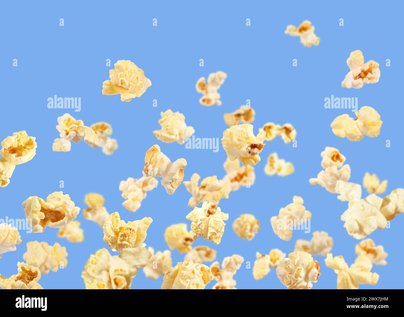 Tasty fresh popcorn flying on blue background Stock Photo - Alamy