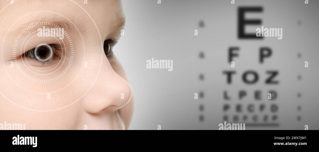 Vision test chart and laser reticle focused on boy's eye against grey ...