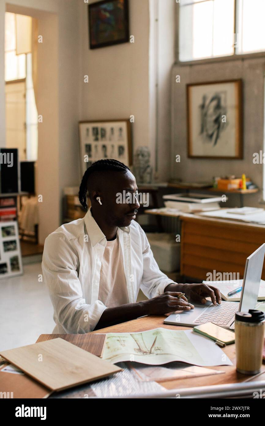 Male entrepreneur working on laptop while sitting at workplace Stock ...