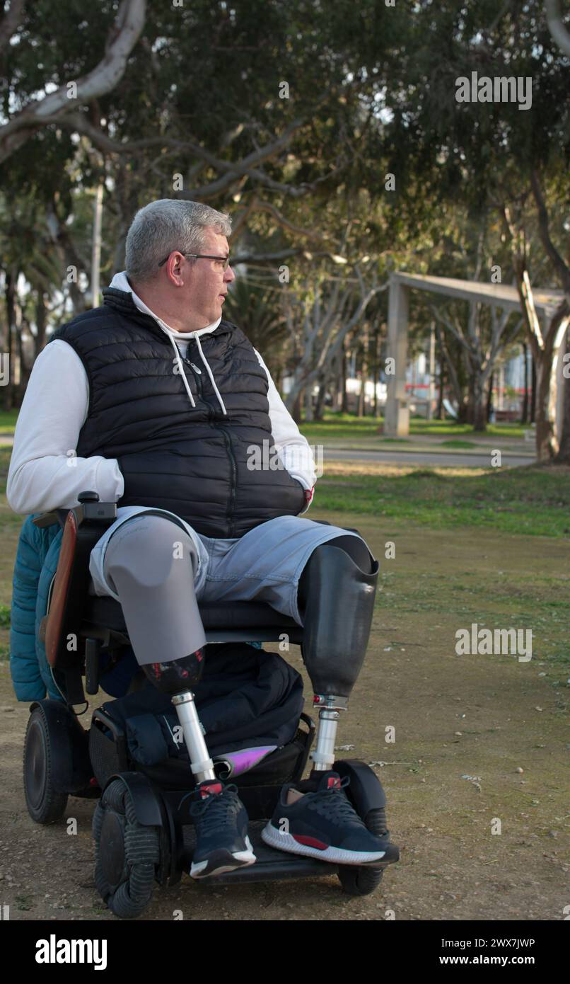 legless man in a wheelchair poses in the park, looking at the horizon ...