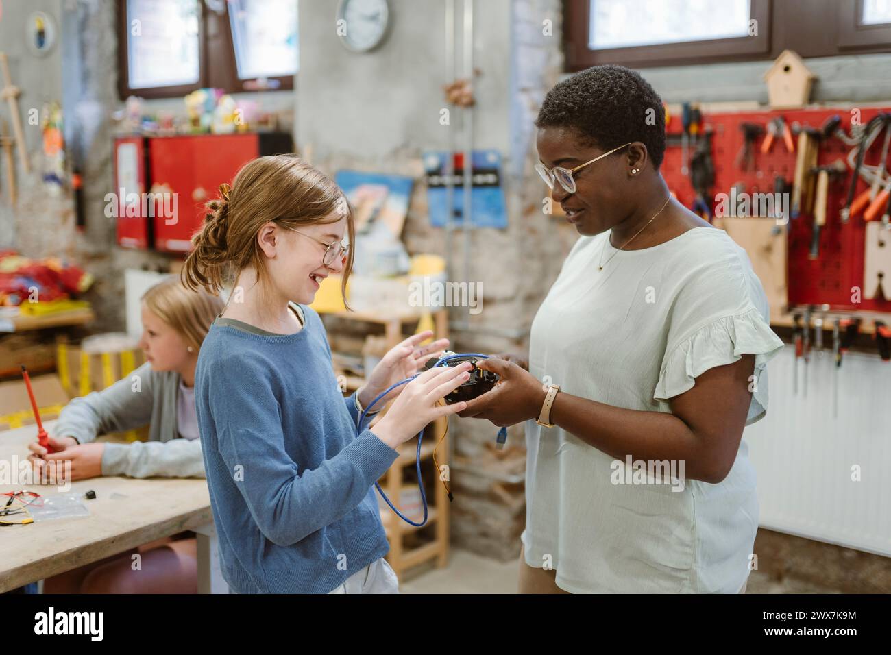 Female teacher explaining electrical component to student at technology ...