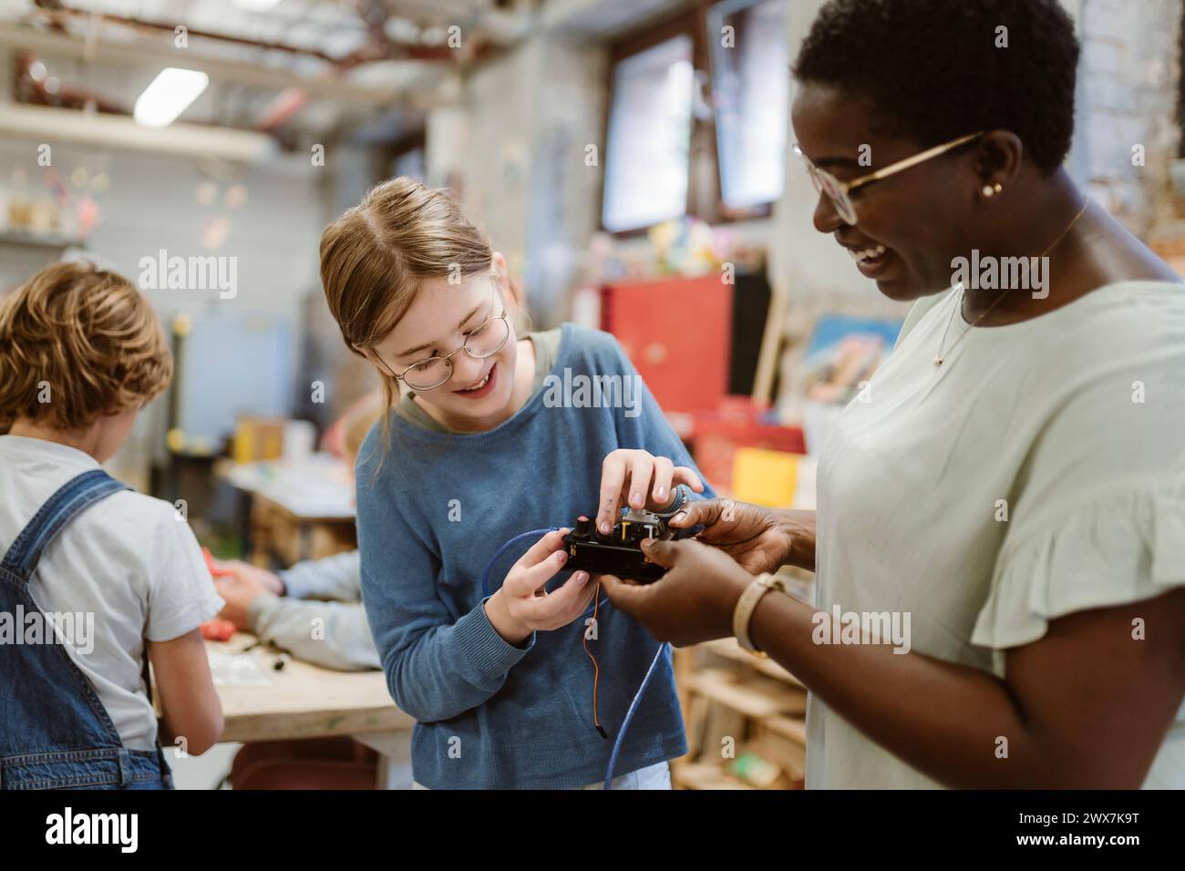 Smiling teacher and student examining electrical component in ...