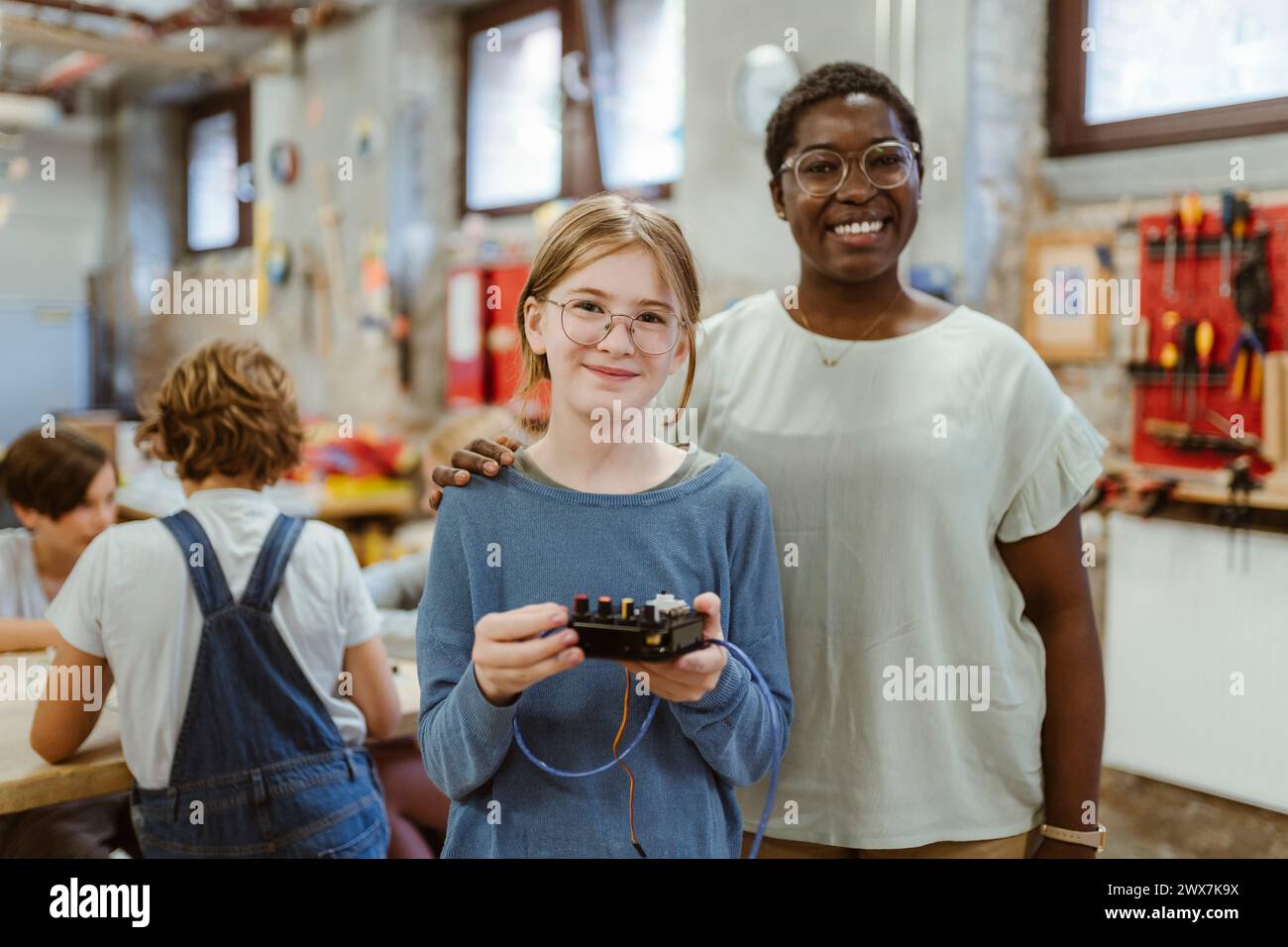 Portrait of smiling teacher with hand on shoulder of female student ...