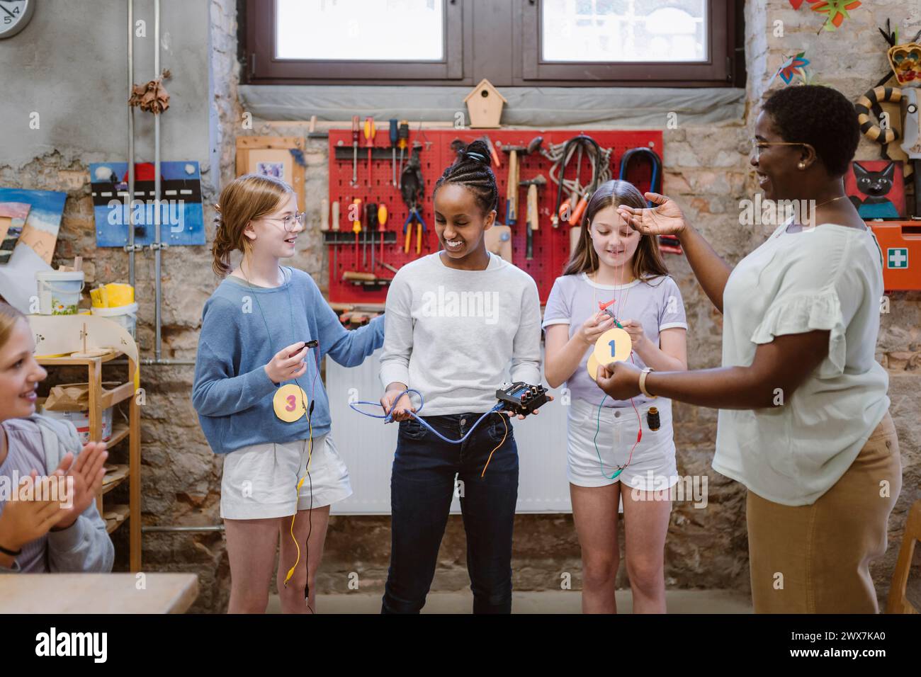 Teacher appraising female students at technology workshop in school ...