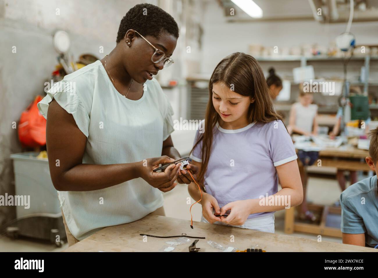 Female teacher explaining electrical part to student at technology ...