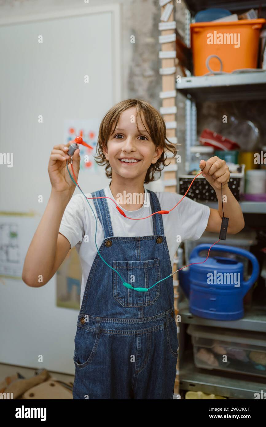 Portrait of smiling female student holding electric motor connected to ...