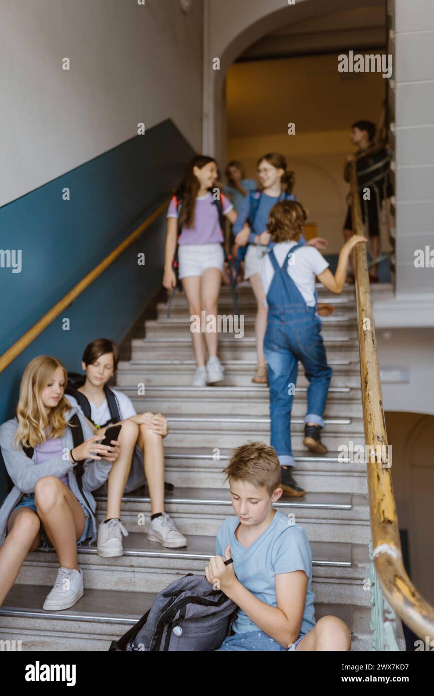 Multiracial male and female students on staircase during recess at ...