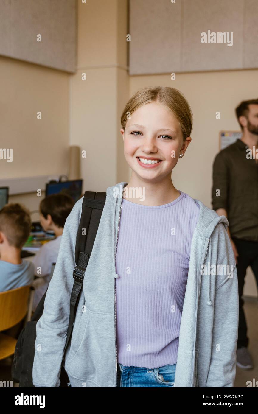 Portrait of smiling female student carrying backpack while standing in ...