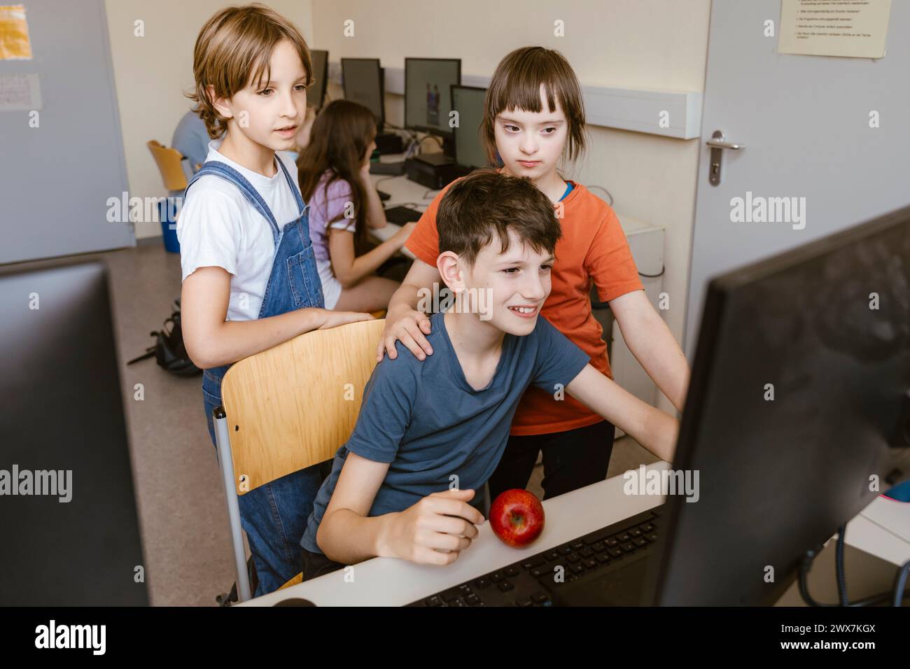 Male and female students with down syndrome girl using computer at desk ...