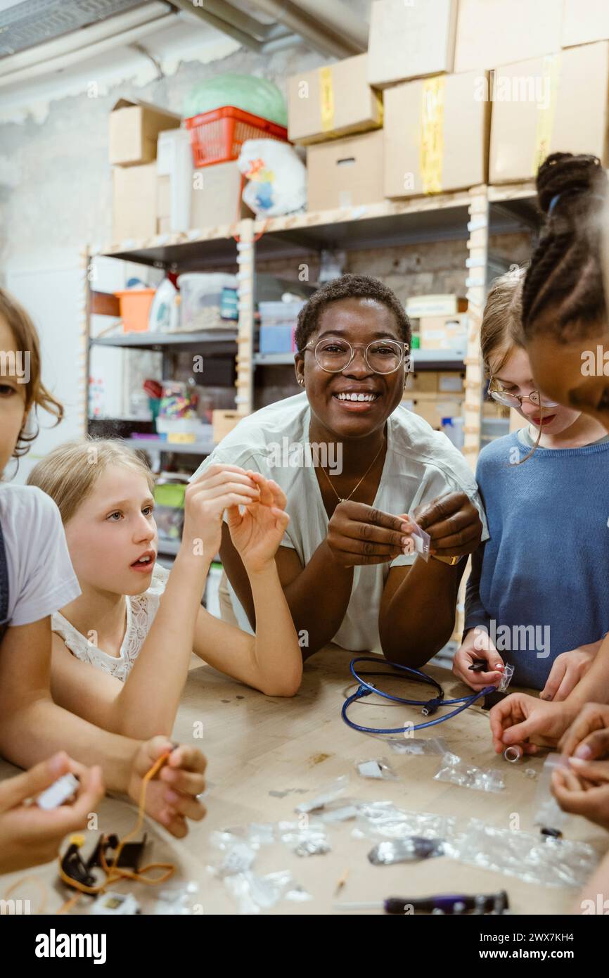 Portrait of smiling female teacher with students working with ...
