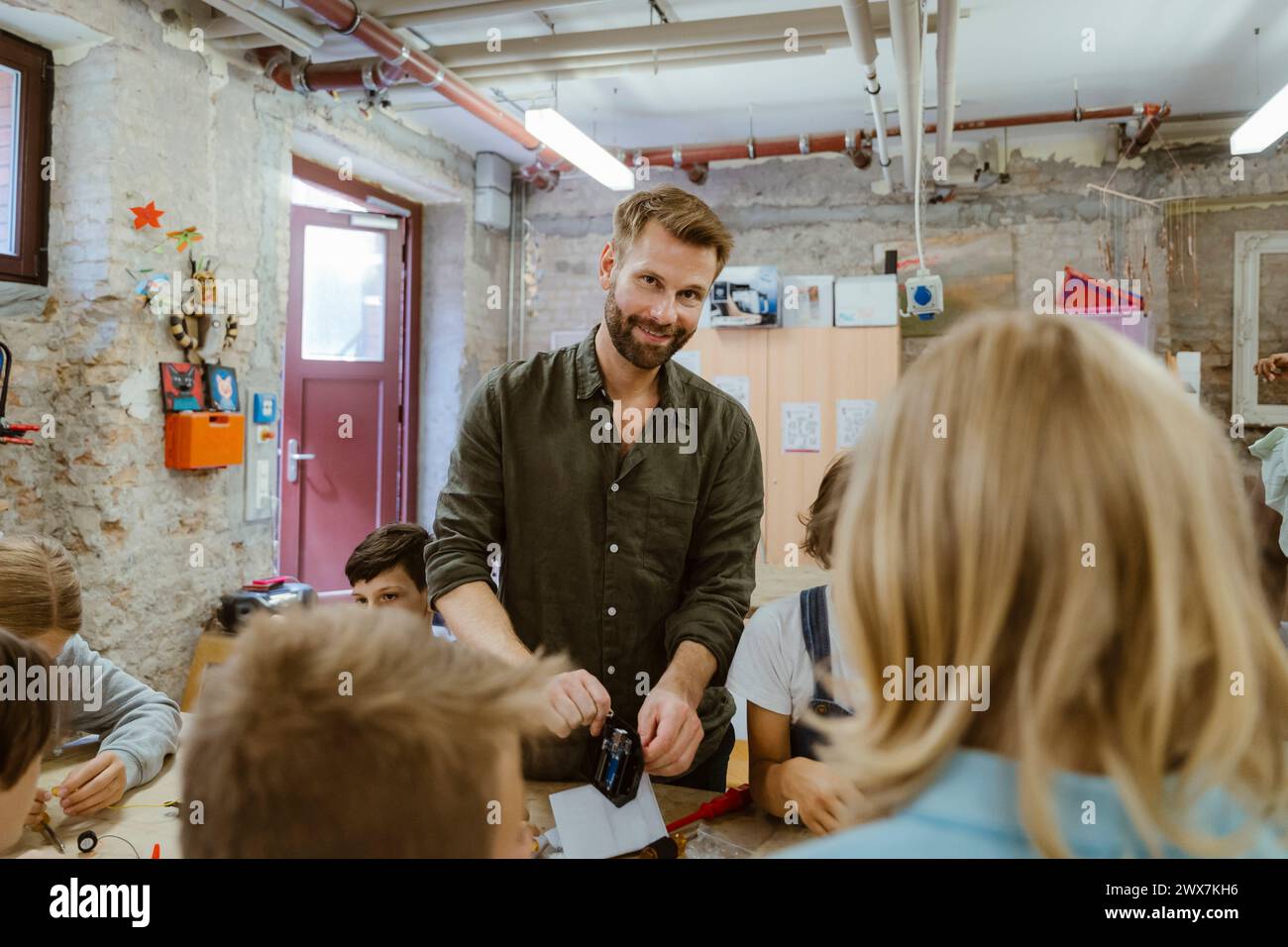 Portrait of smiling male teacher teaching students to work with ...