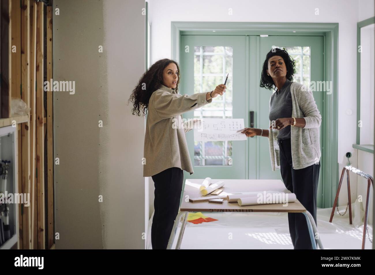 Side view of female design professional explaining blueprint to client ...