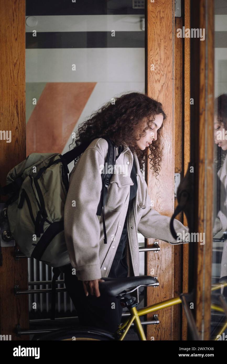 Female architect carrying backpack while leaving with bicycle from ...