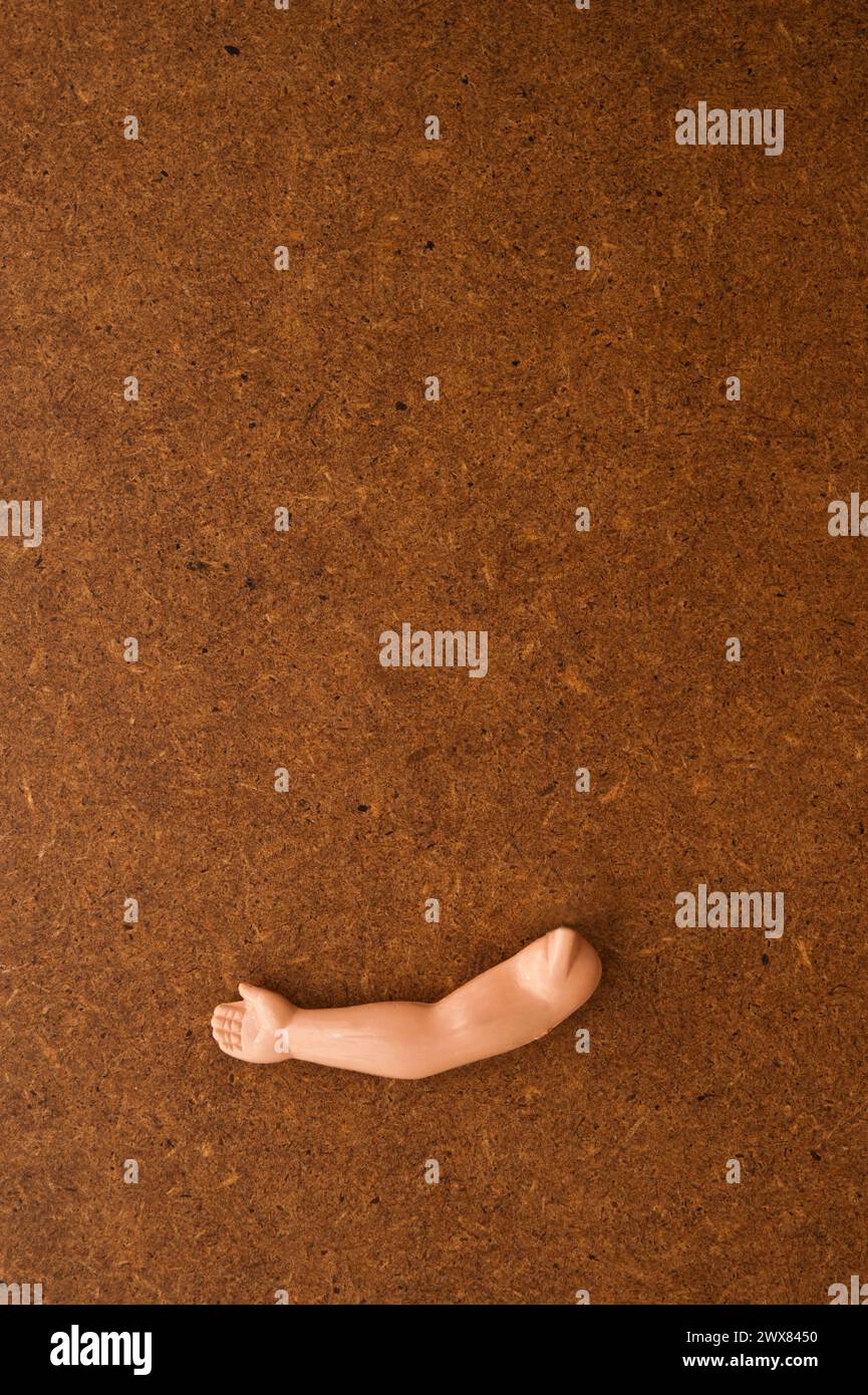 plastic doll arm on a brown background Stock Photo - Alamy