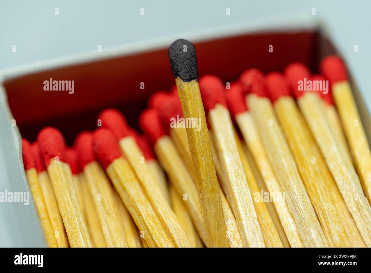 Set of several defocused black headed matchsticks with one green-headed ...