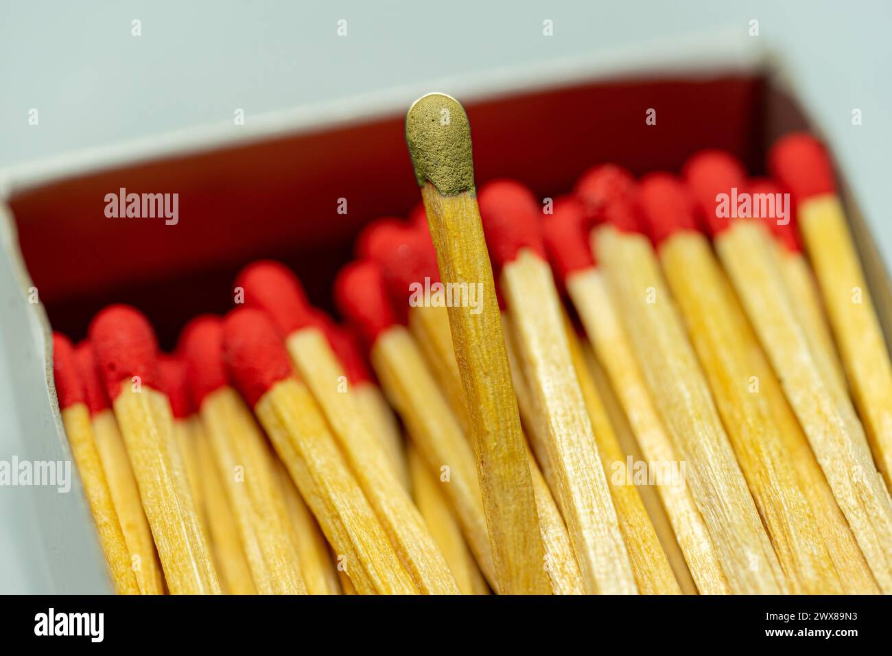 Set of several defocused red-headed matchsticks with one yellow headed ...