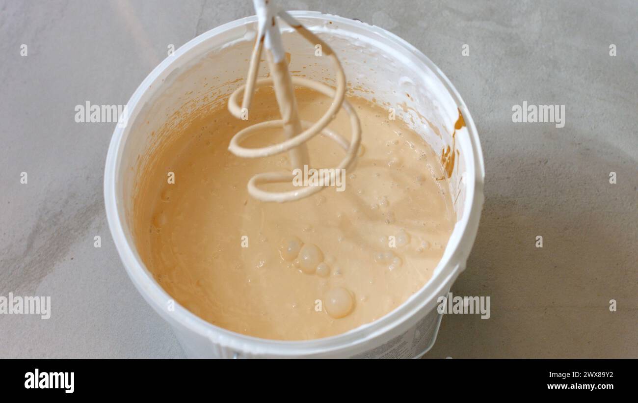 Preparation of paint for painting walls. A mixer and a bucket of paint ...