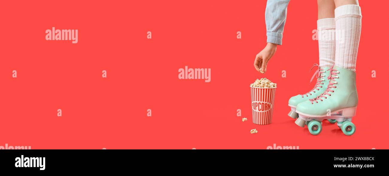 Bucket of popcorn and legs of woman in roller skates on red background ...