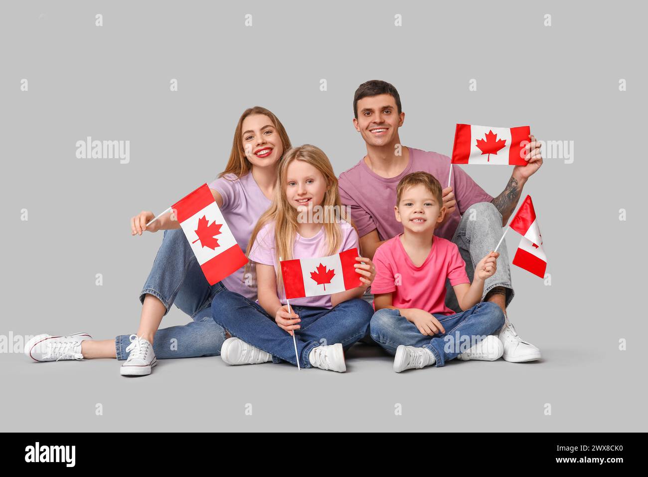 Happy family with flags of Canada sitting on grey background Stock ...
