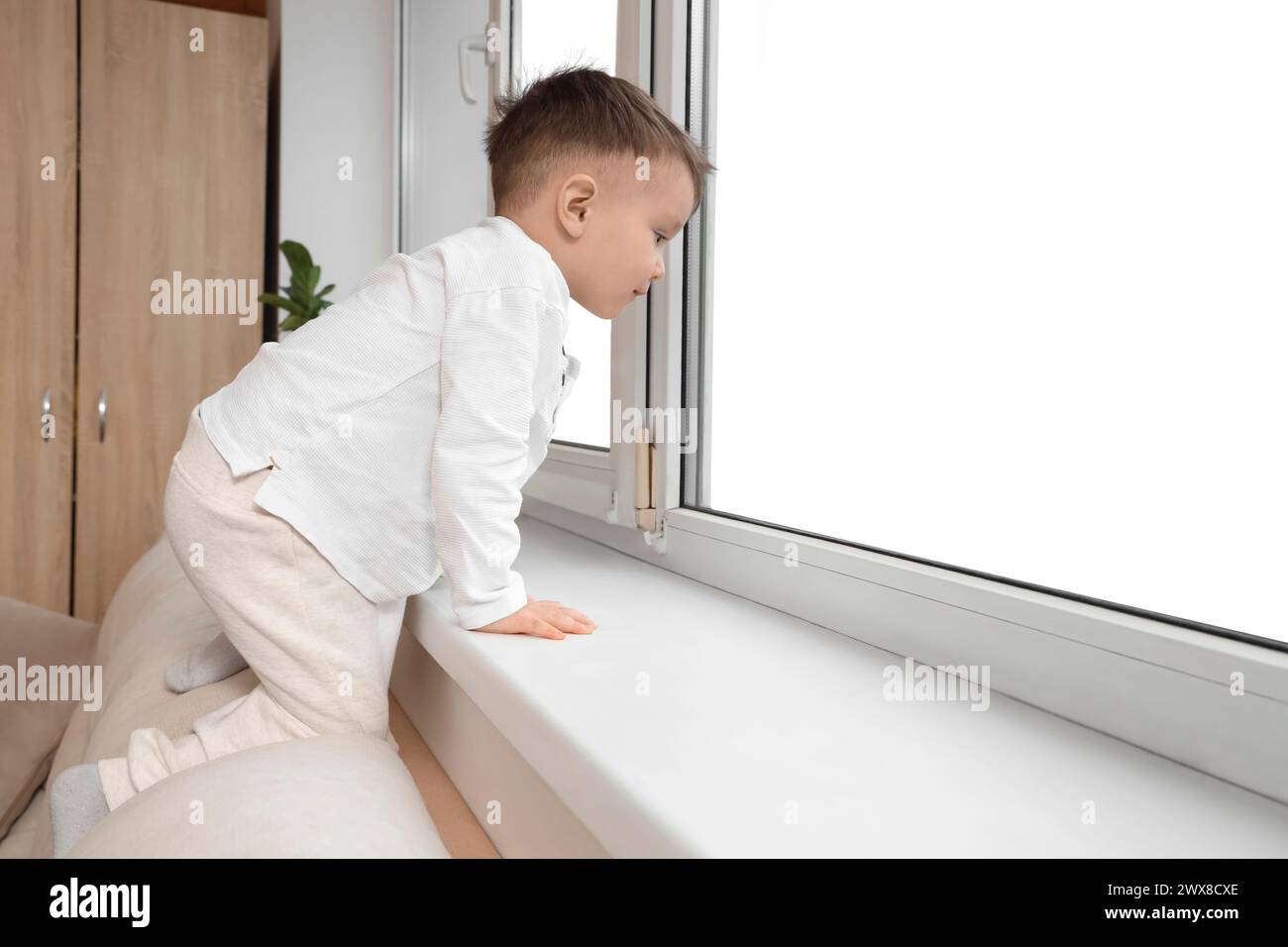 Little boy climbing on windowsill at home. Child in danger Stock Photo ...