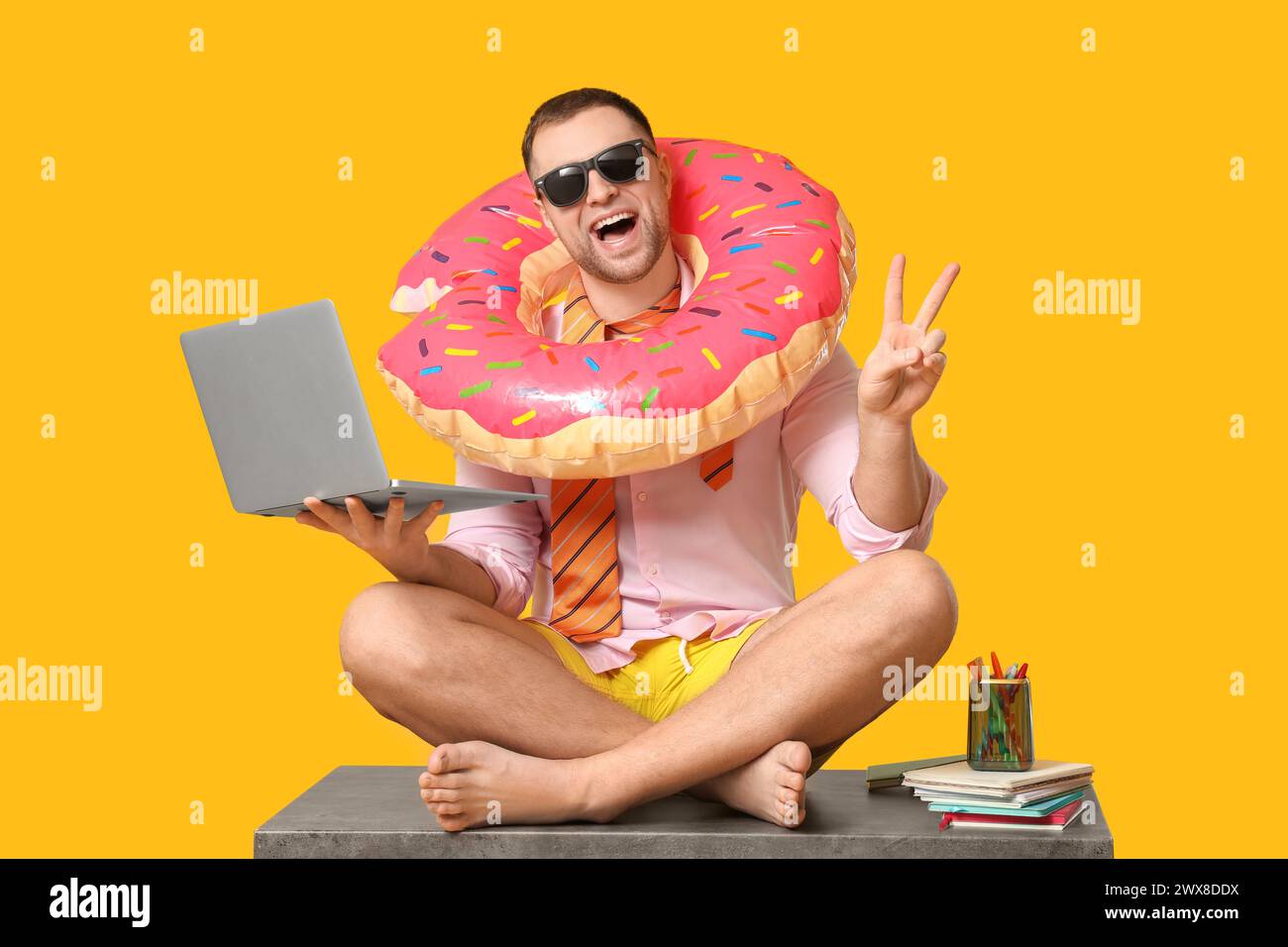 Happy office worker in sunglasses with inflatable ring and laptop ...