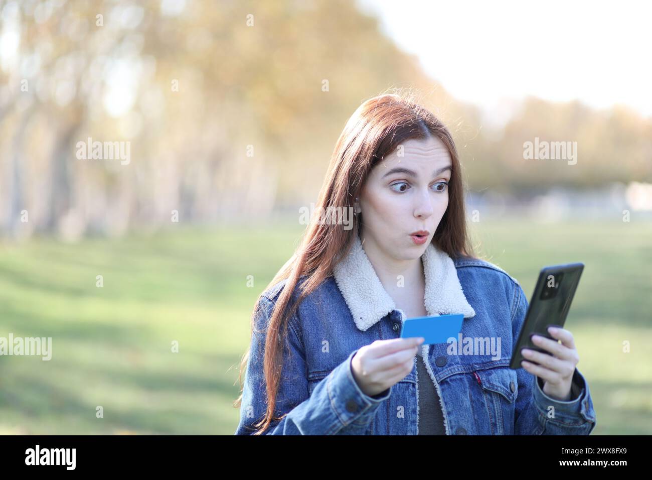 Woman makes a surprised gesture while holding her credit card and ...